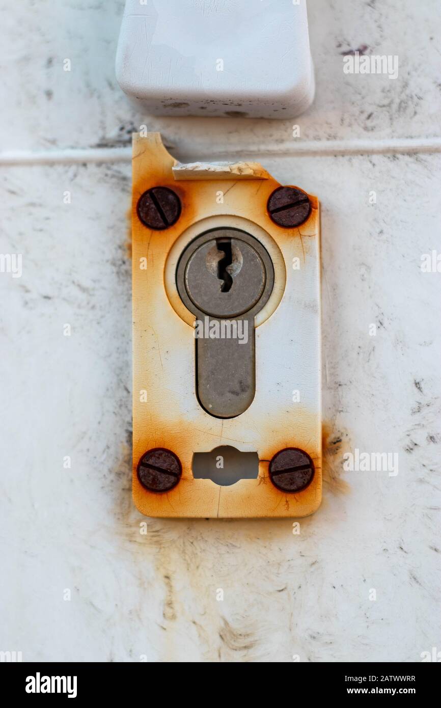Rusted grey metal keyhole on white plastic background, broken cover old ...