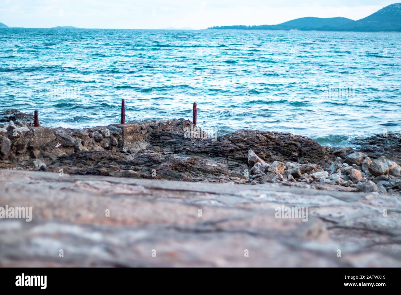 Natural stone formation on a beach shore. Iron poles forming a wall in ...