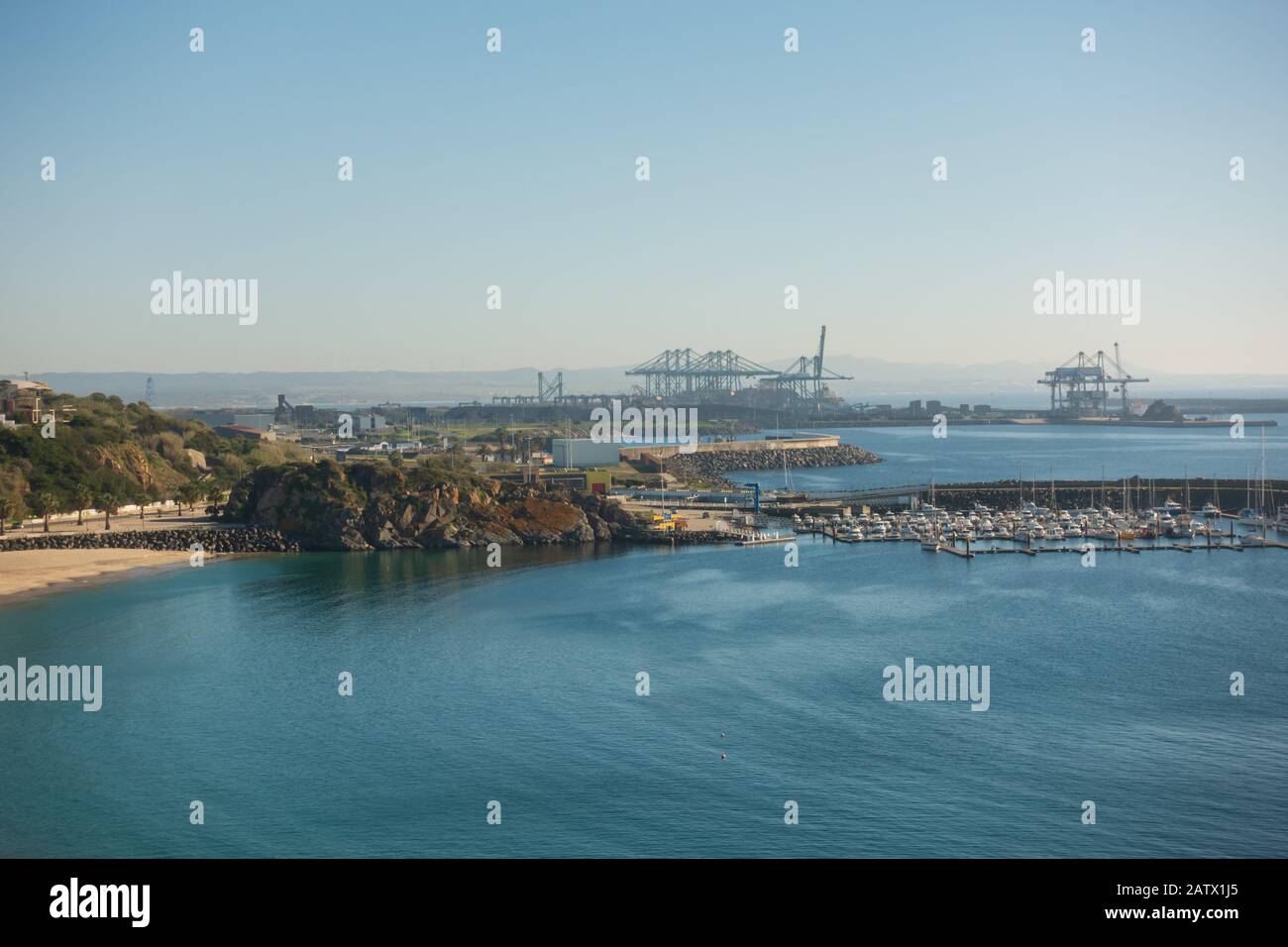 Sines beach at sunset with container port terminal cranes behind, in ...