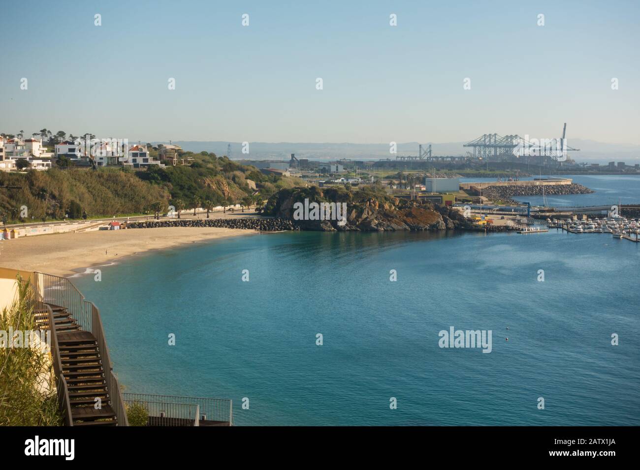 Sines beach at sunset with container port terminal cranes behind, in ...