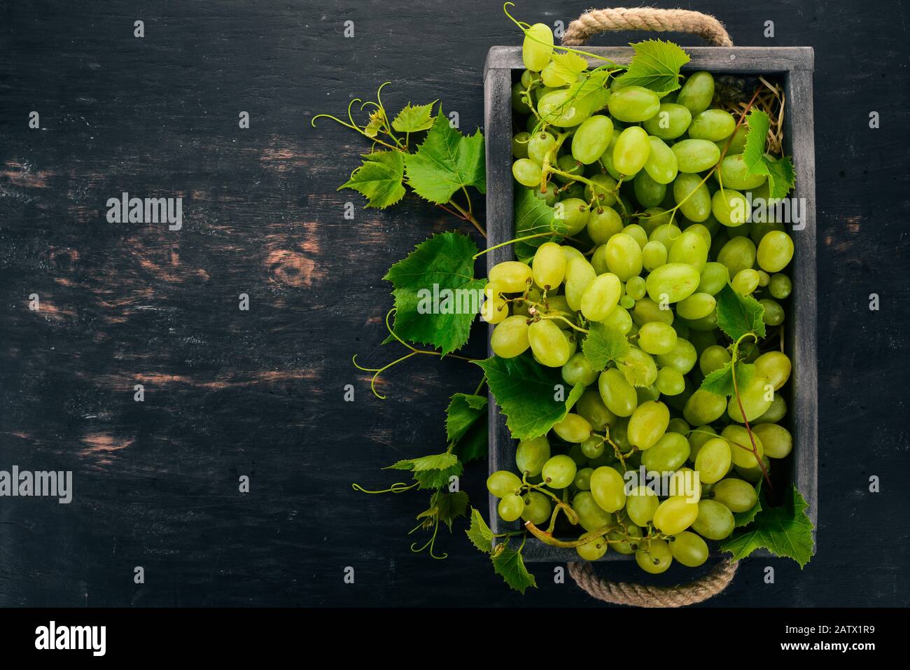 Grapes in a wooden box. Leaves of grapes. Top view. On a black ...