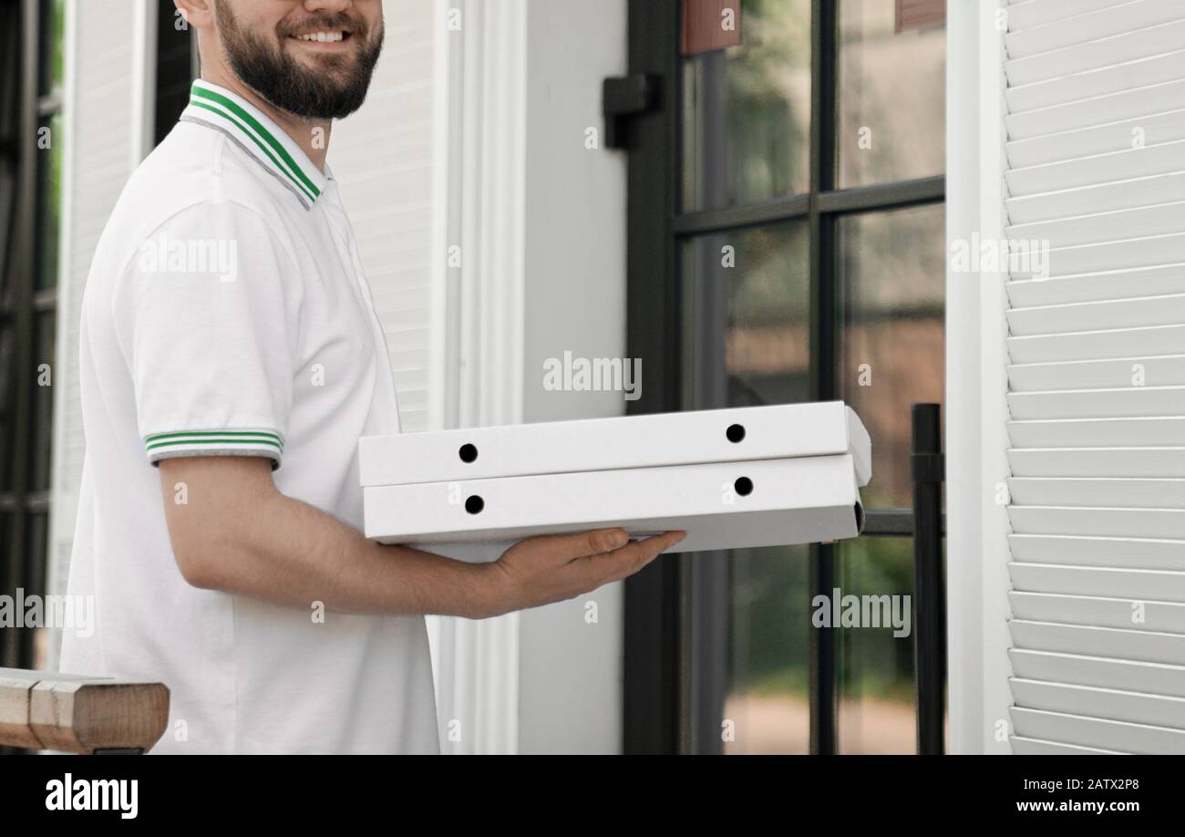 Crop of incognito happy joyful young male courier in white polo ...