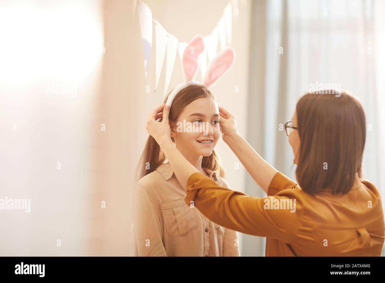 Mother wearing rabbit ears on her daughter's head they preparing ...