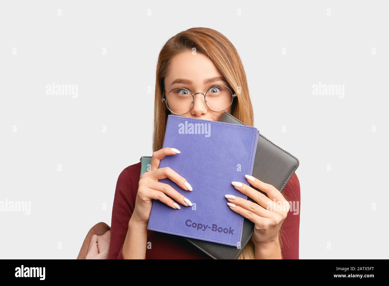 Student looks in camera hiding behind books Studio Stock Photo - Alamy