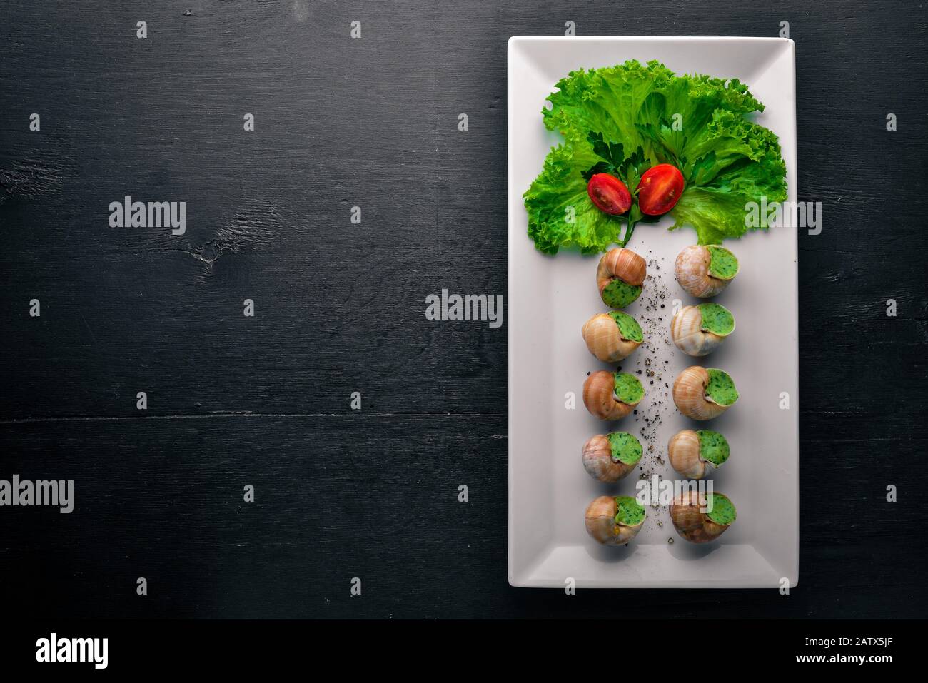 French and Italian cuisine. Baked snails. On a wooden background. Top ...