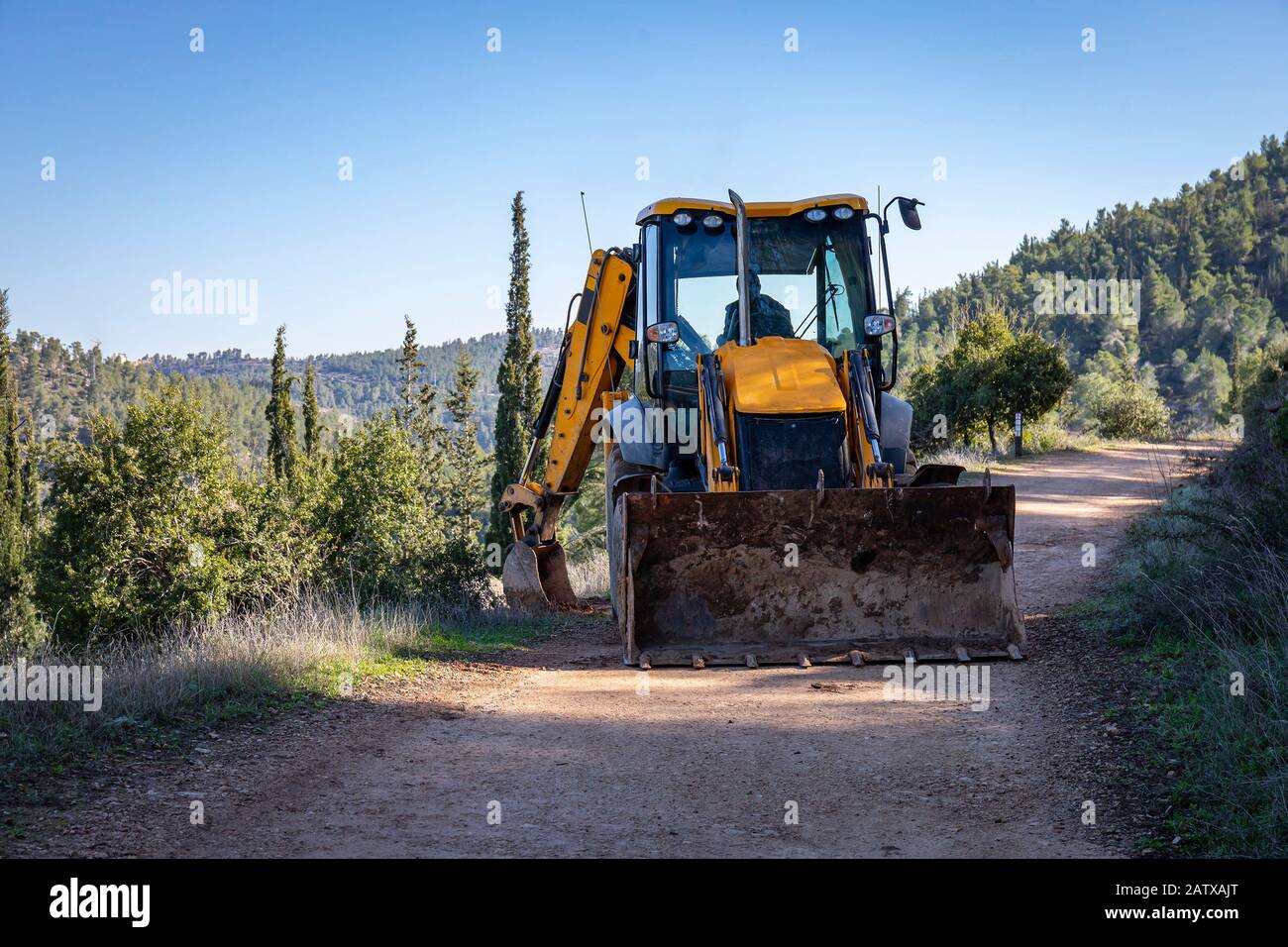 A backhoe loader working on a path in a forest near Jerusalem, Israel ...