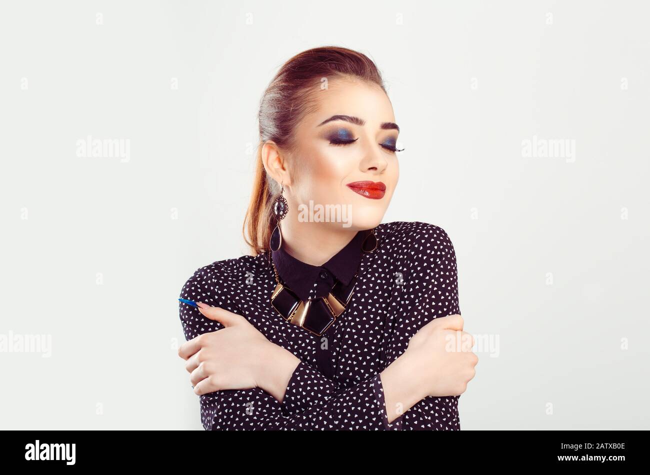 Woman embraces her self eyes closed, has a facial expression of ...