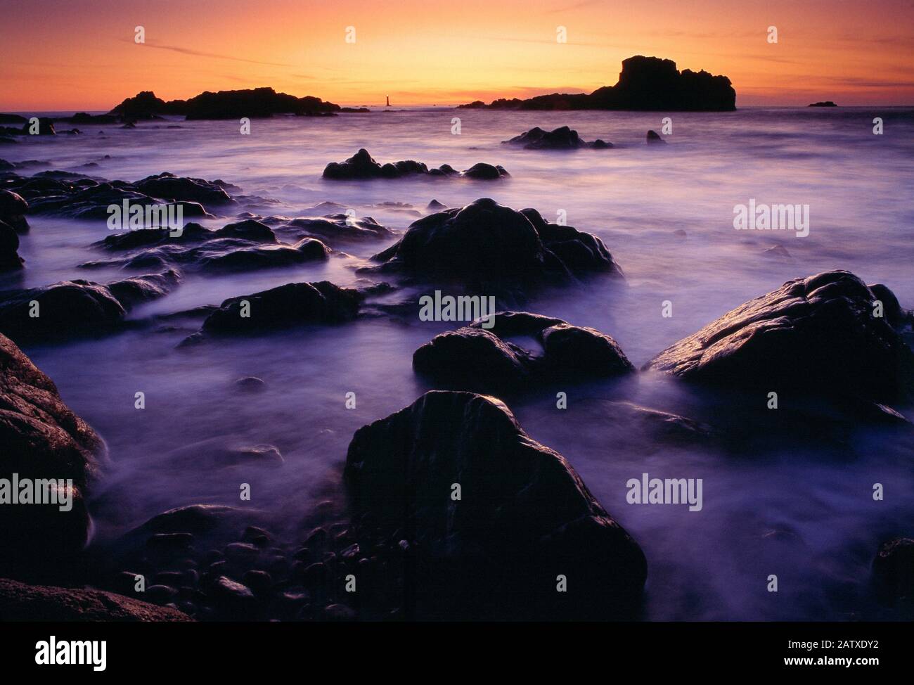 Guernsey. Coast view at sunset with distant Les Hanois lighthouse Stock ...