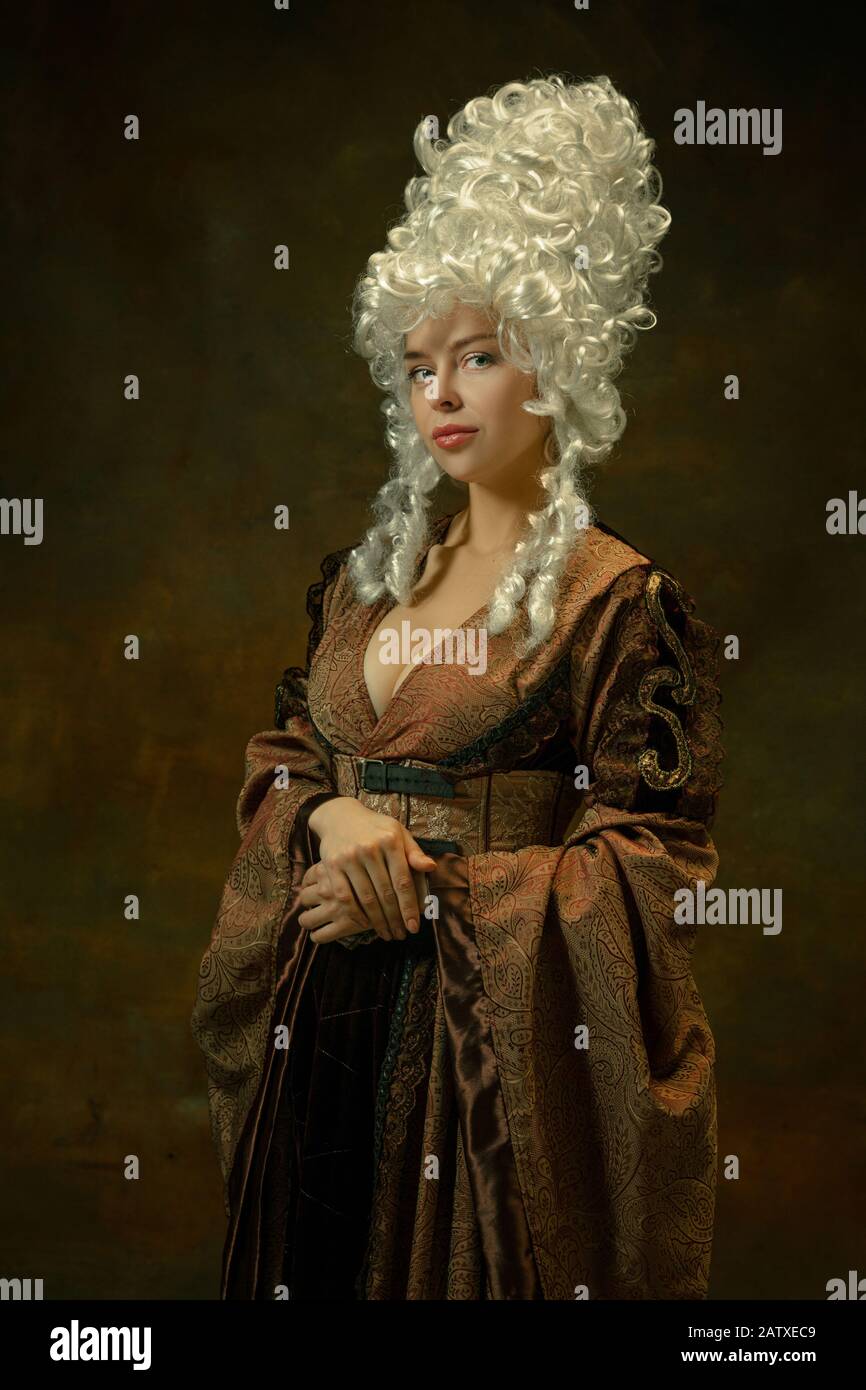 Portrait of medieval young woman in brown vintage clothing standing on ...