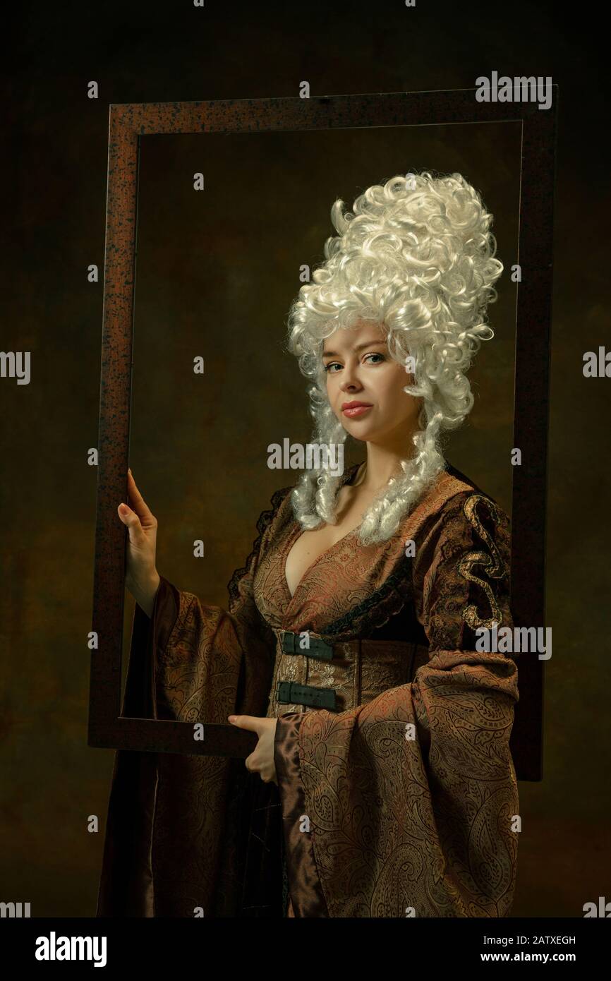 Calm. Portrait of medieval young woman in vintage clothing with wooden ...