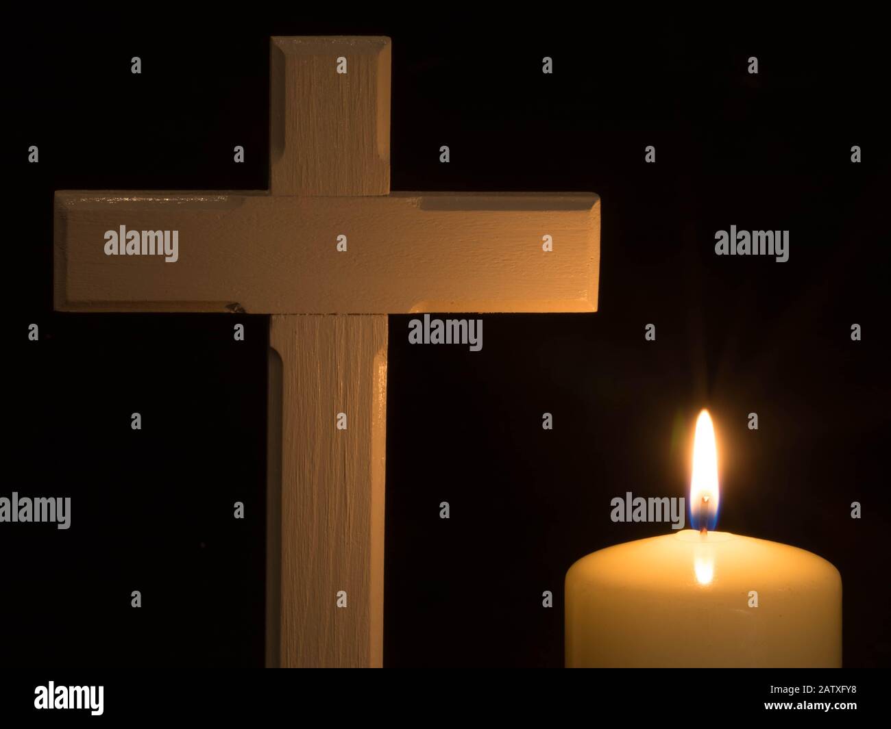 Burning candle under Jesus cross in a cemetery against black background ...