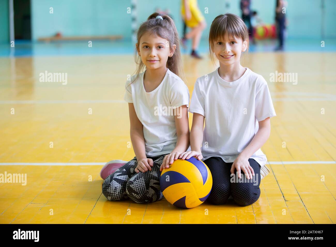 Two girls schoolgirl with a ball in the gym. Portrait of a child ...