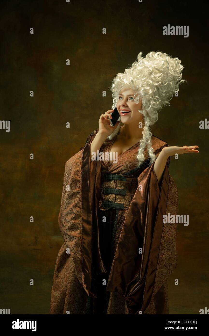 Talking on phone. Portrait of medieval young woman in brown vintage ...