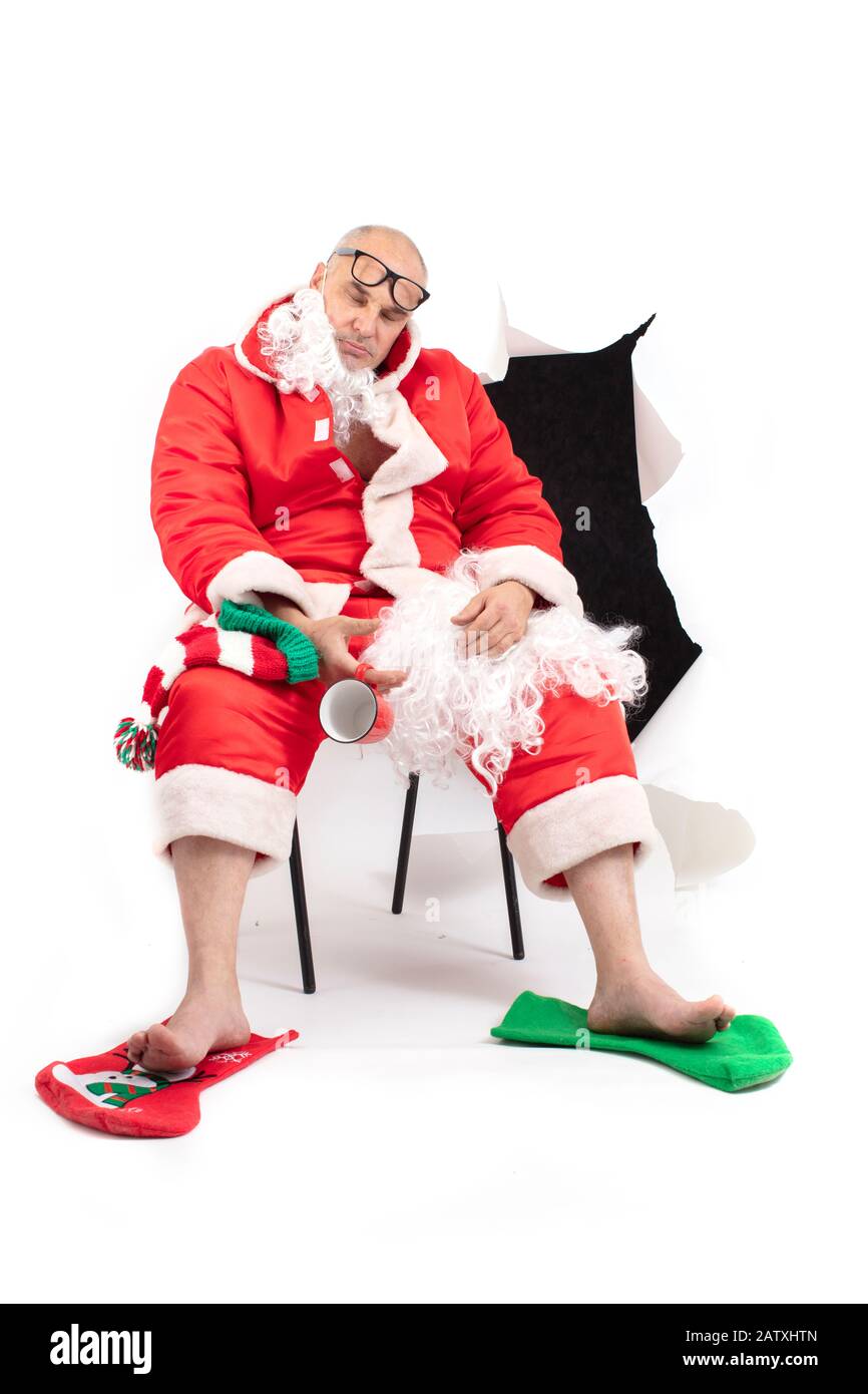 Tired Santa Claus. A man in a red Christmas costume sleeps on a chair ...
