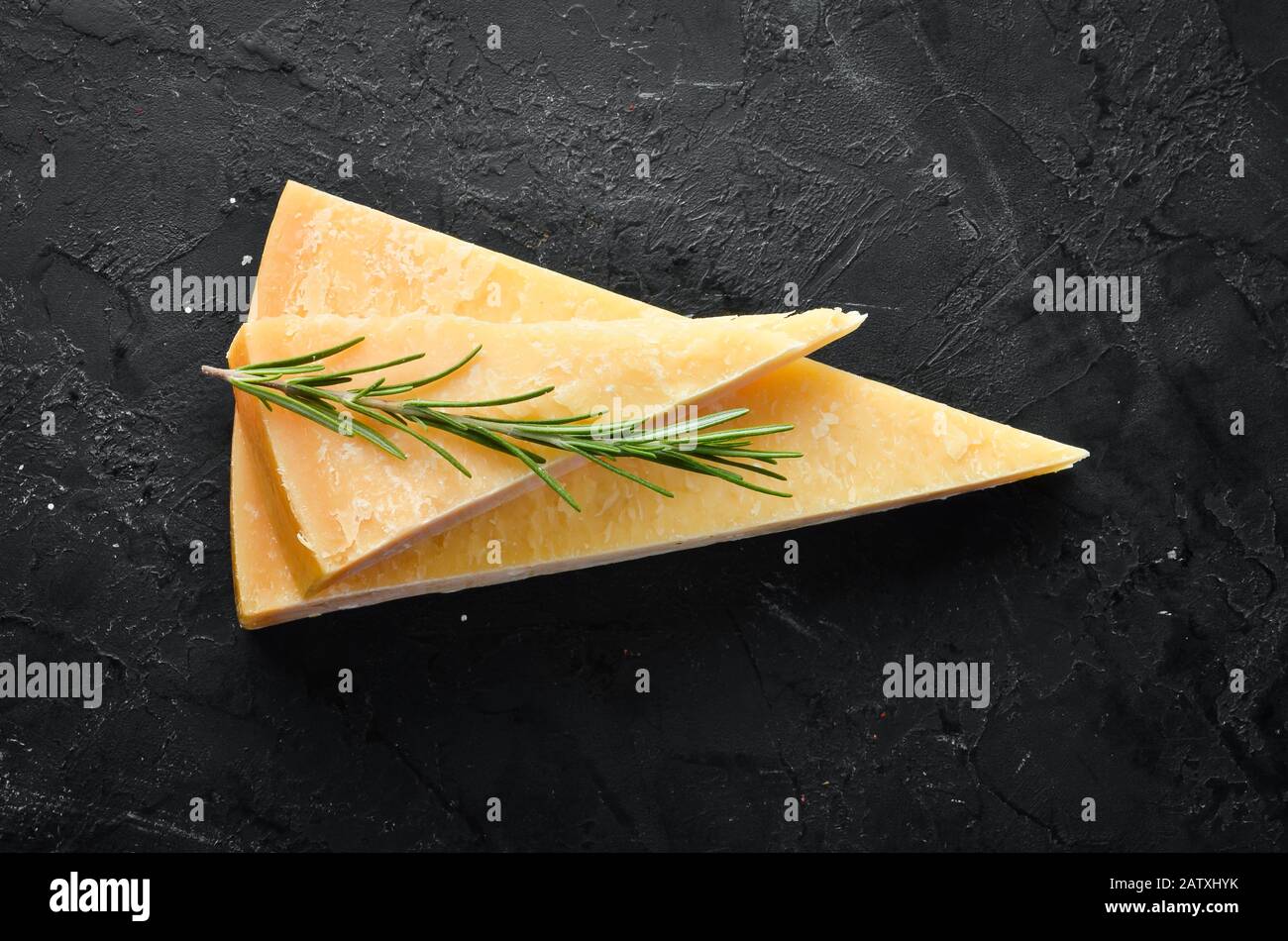 Piece of solid cheese on a black stone background. Parmesan. Top view ...
