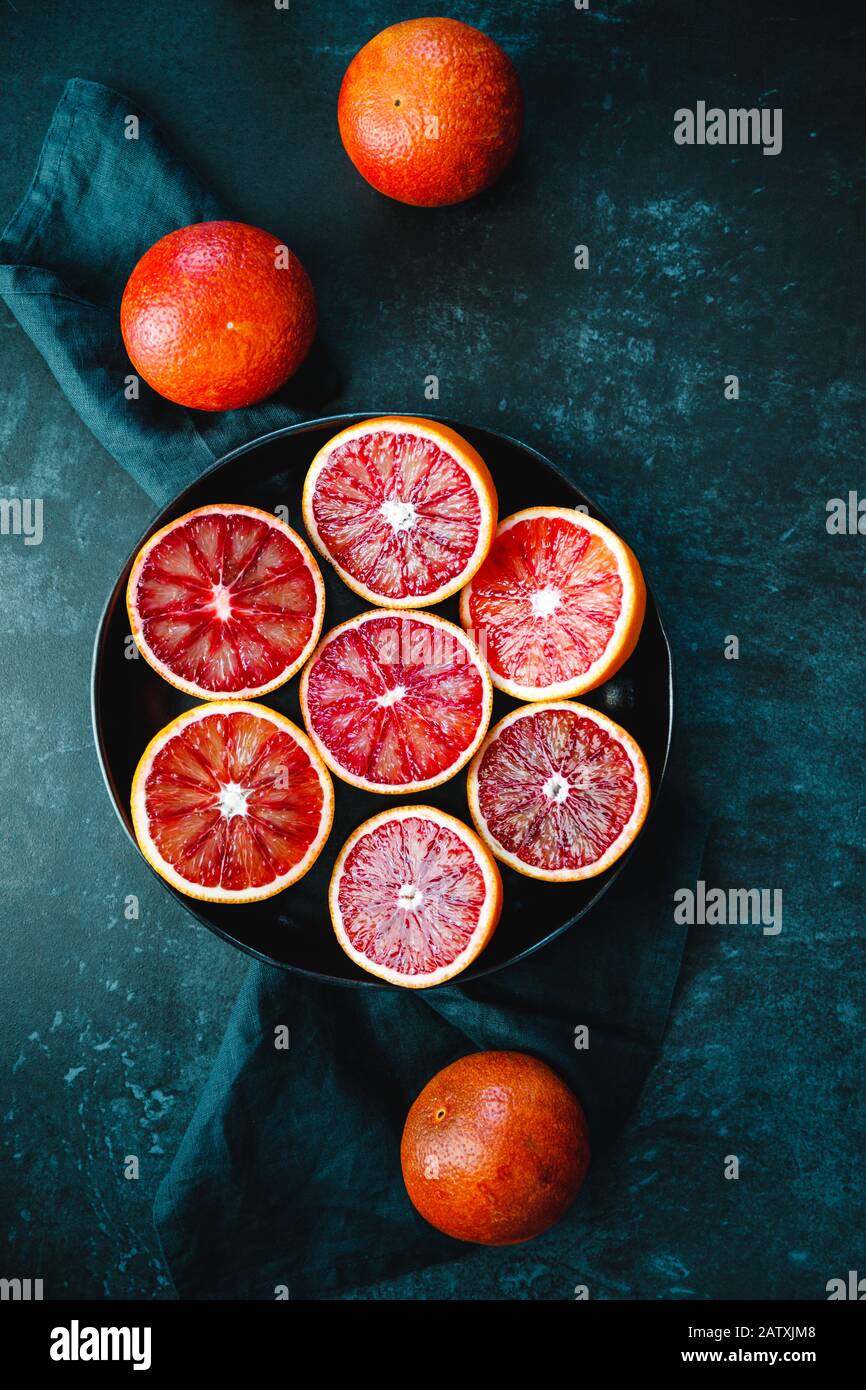 Flat lay food composition with blood oranges on a dark blue background ...