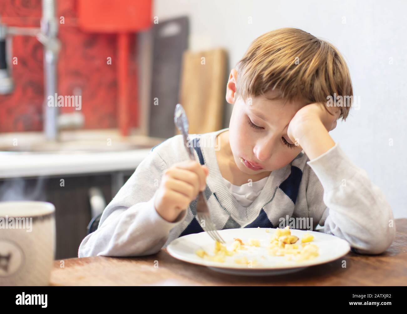 The child does not want to eat. Poor appetite. A boy sits over a plate ...