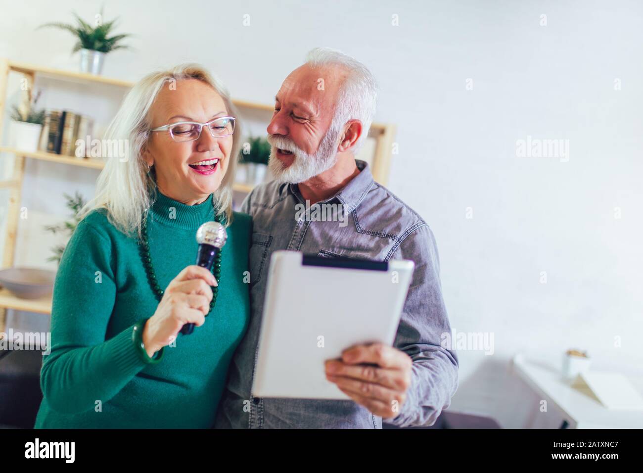 Senior couple singing karaoke at home, having fun Stock Photo - Alamy