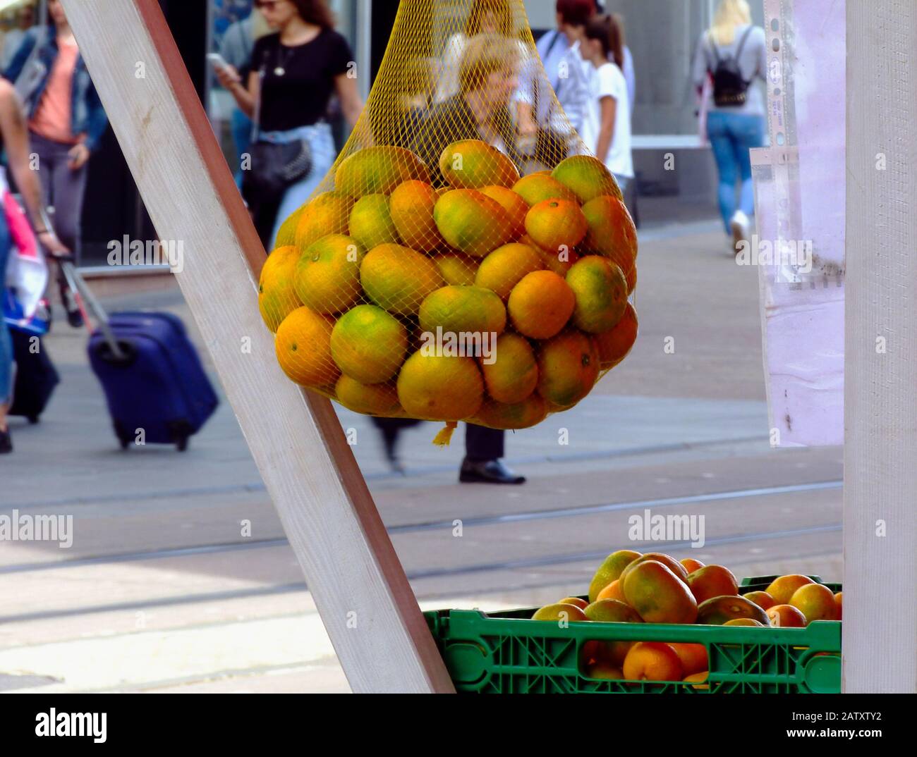 fruit vendor stand. orange, yellow and green clementines. vinyl net ...