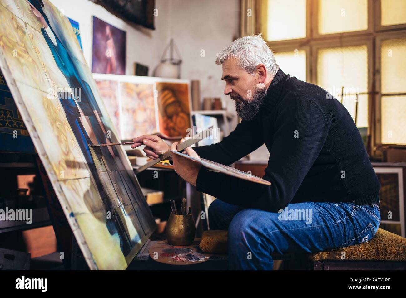 Mature man painting on canvas in art studio Stock Photo - Alamy