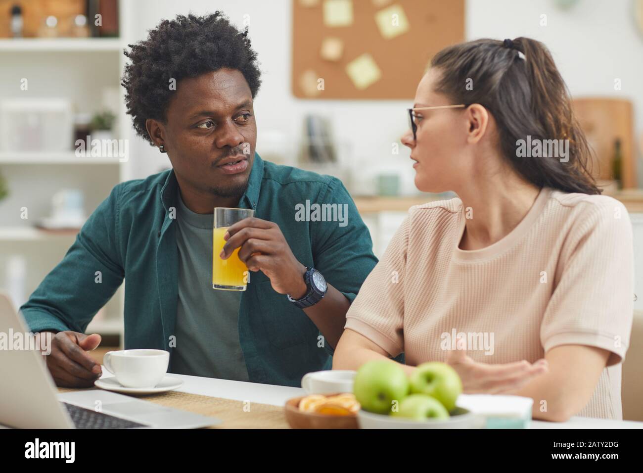 African young man drinking juice and talking to young woman while ...