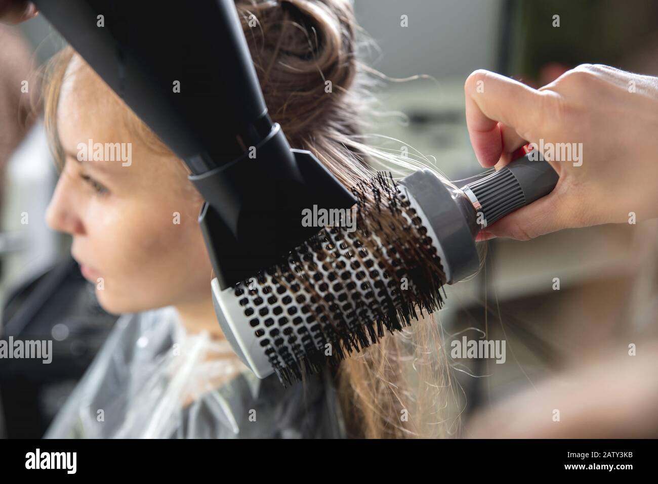 Close up of hairdressers hands drying long blond hair with blow dryer ...