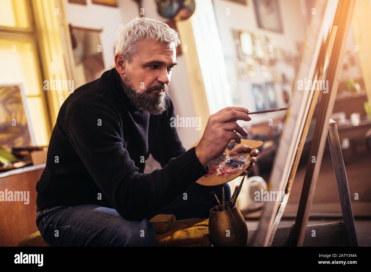 Mature man painting on canvas in art studio Stock Photo - Alamy