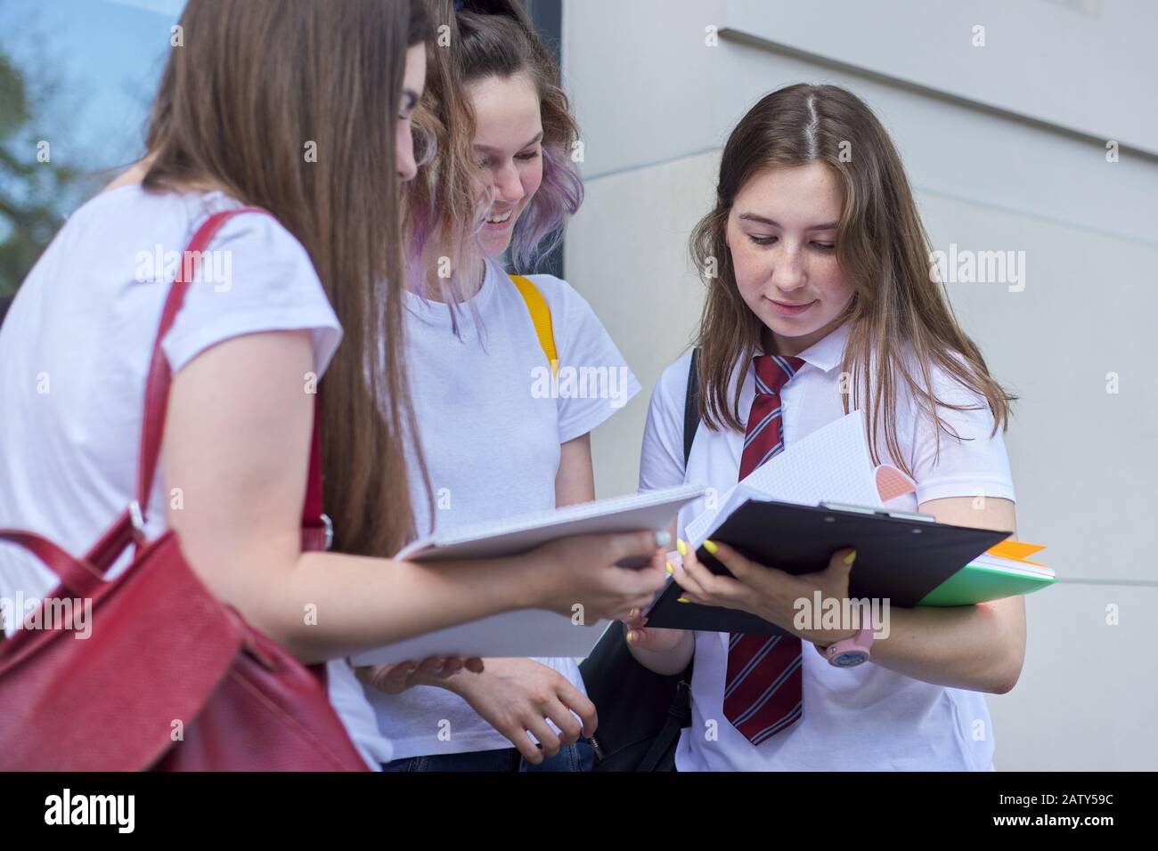 Talking student girls. Three teenagers with backpacks books, outdoor ...