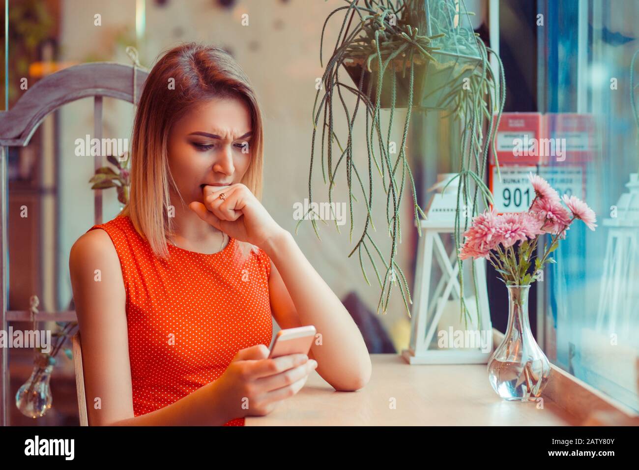 Biting fist and looking at cellphone. Side view of a girl angry with ...