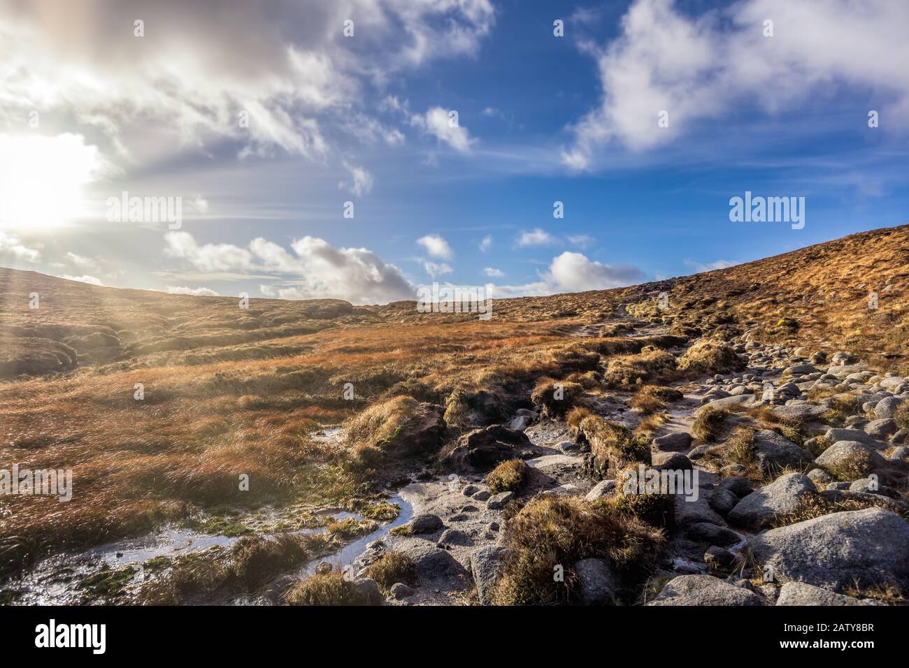 Wet and rocky field on the bank of Slieve Donard mountain with blue sky ...