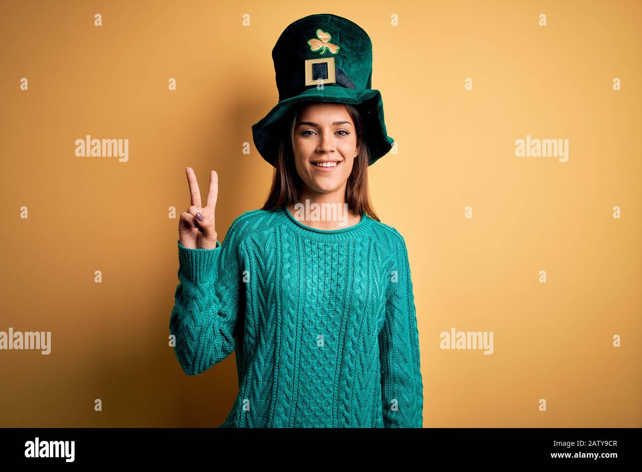 Young beautiful brunette woman wearing green hat with clover ...