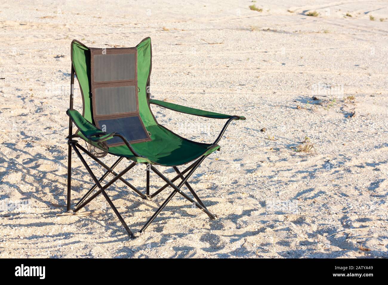 A portable foldable solar panel hangs on a travel chair. Tourist ...