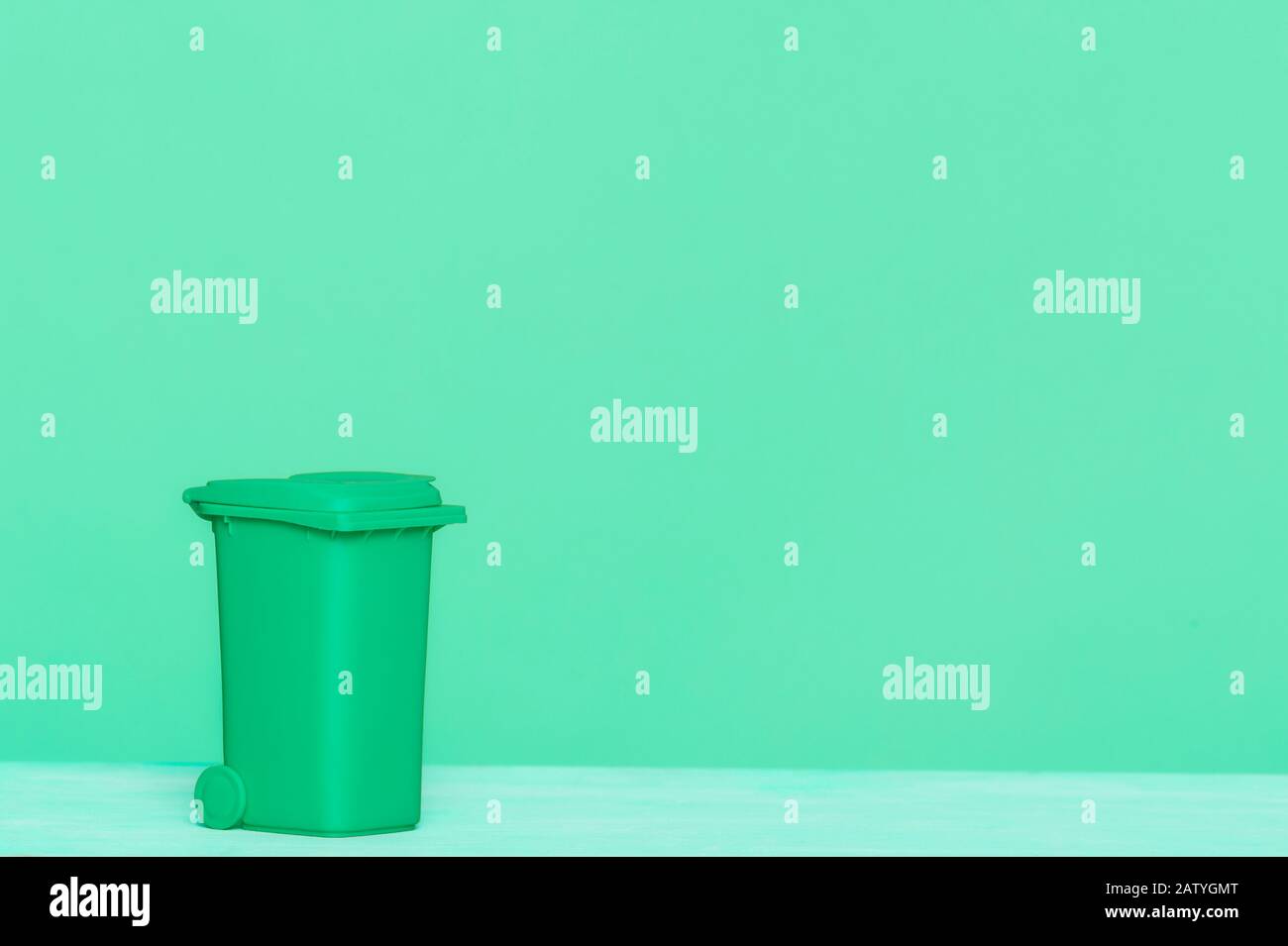 A green plastic garbage bin on green background, great for recycling ...