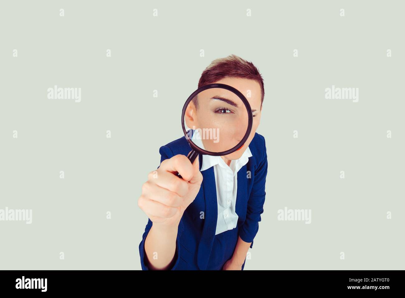 Skeptical woman looking through magnifying glass isolated yellow wall ...
