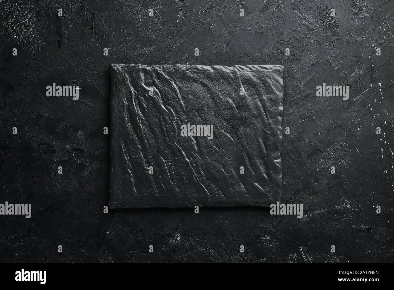 Square black stone dish. On a black stone background. Top view. Free ...