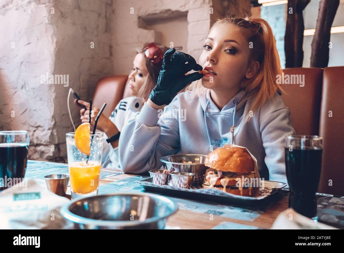 Two teenage girls sitting in cafe together Stock Photo - Alamy