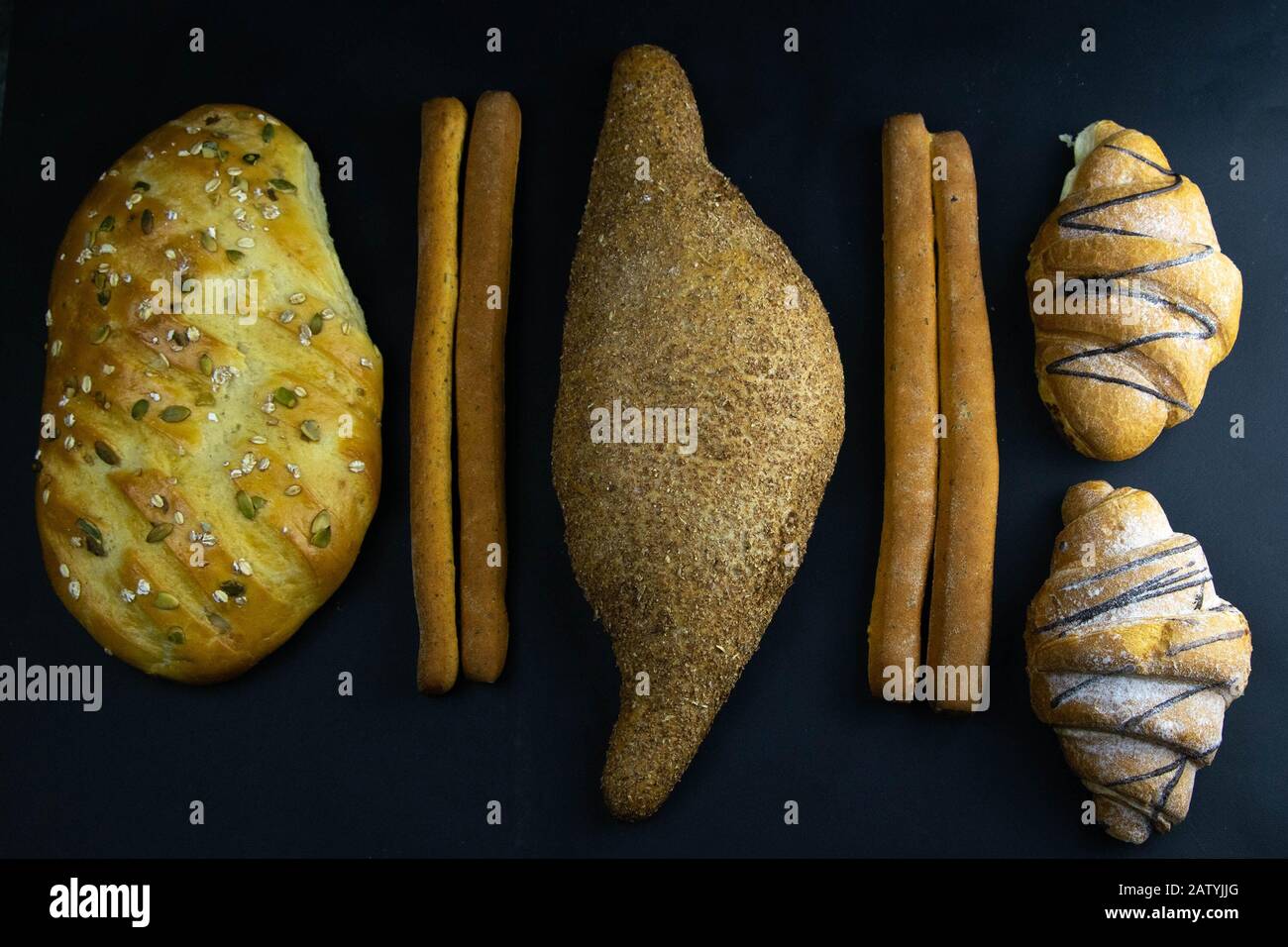 Different types of fresh bread with grain on a black rustic background ...