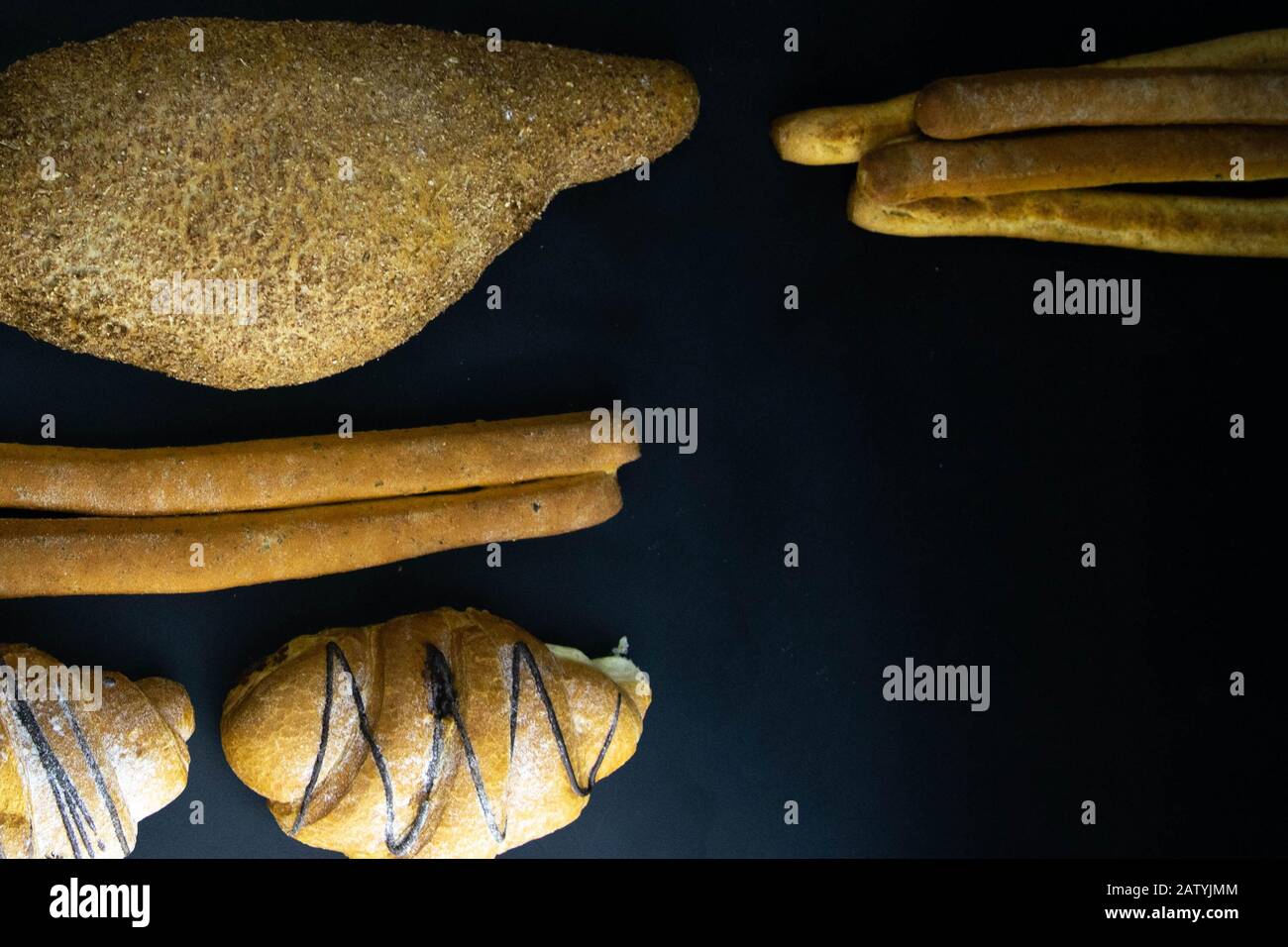 Different types of fresh bread with grain on a black rustic background ...