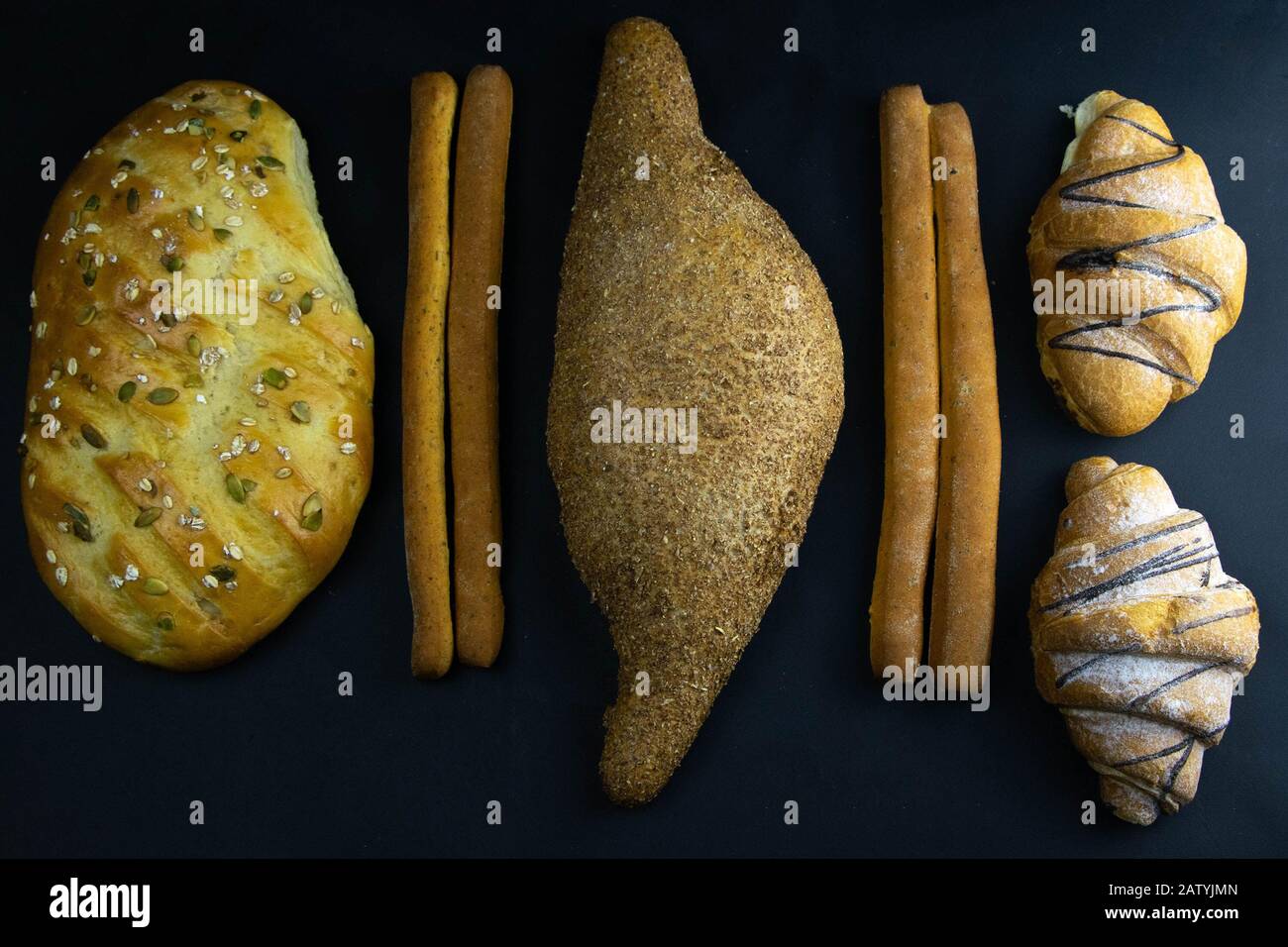 Different types of fresh bread with grain on a black rustic background ...