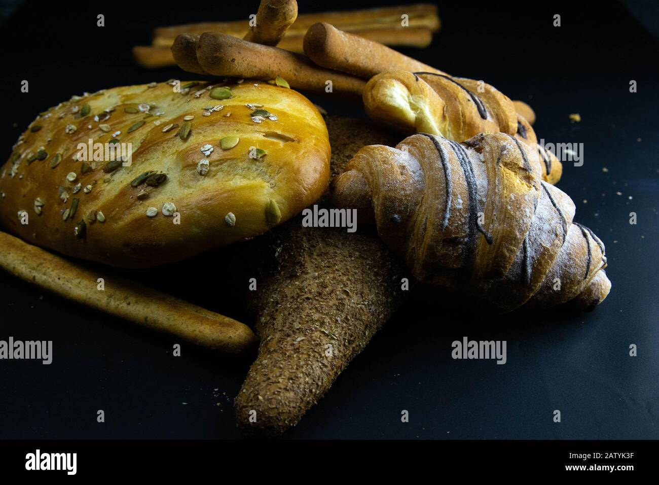 Different kinds of fresh bread with grain on black rustic background ...
