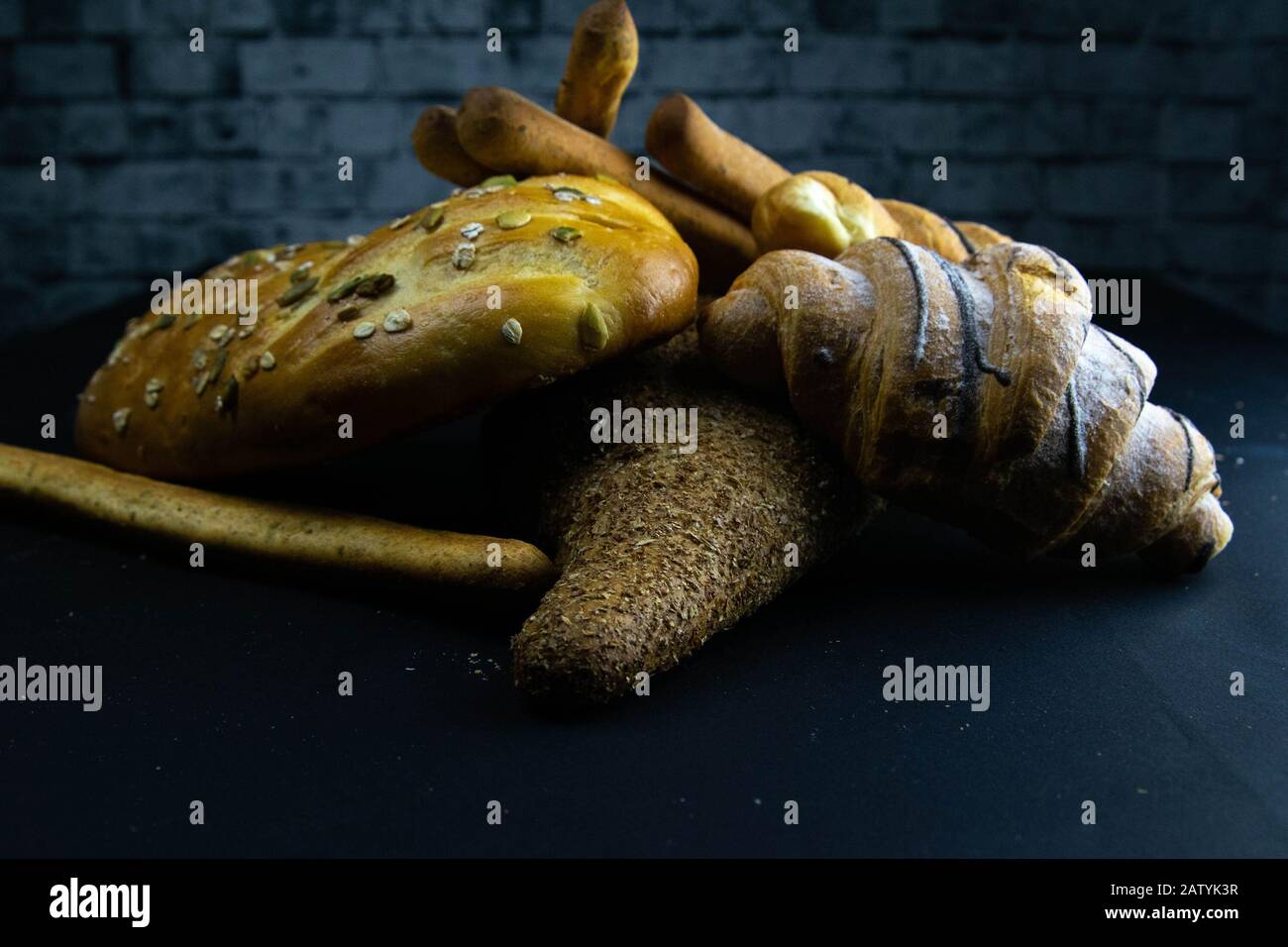 Different kinds of fresh bread with grain on black rustic background ...
