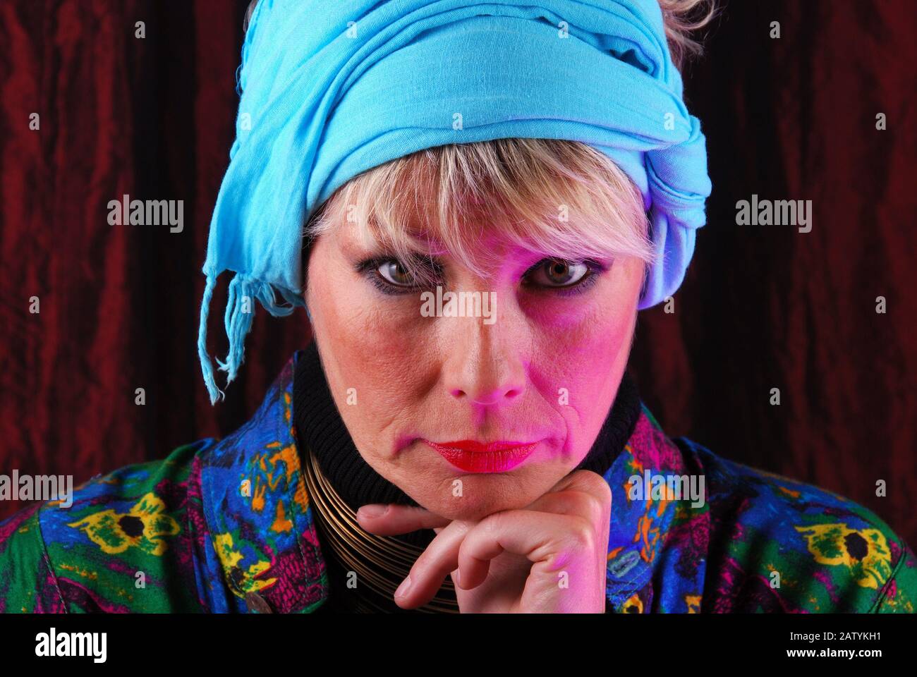 Mysterious woman with gypsy look illuminated by purple light looking at ...