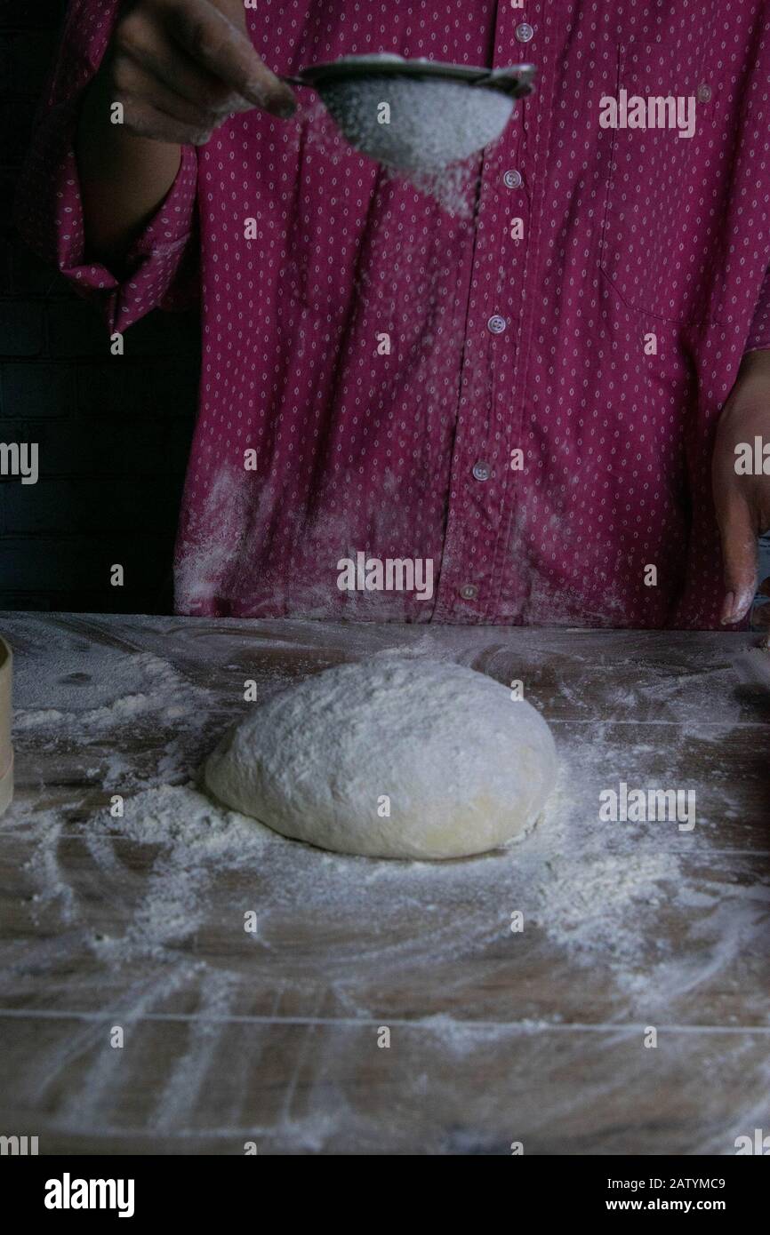 The woman sprinkles flour dough from the fullness for sifting flour ...