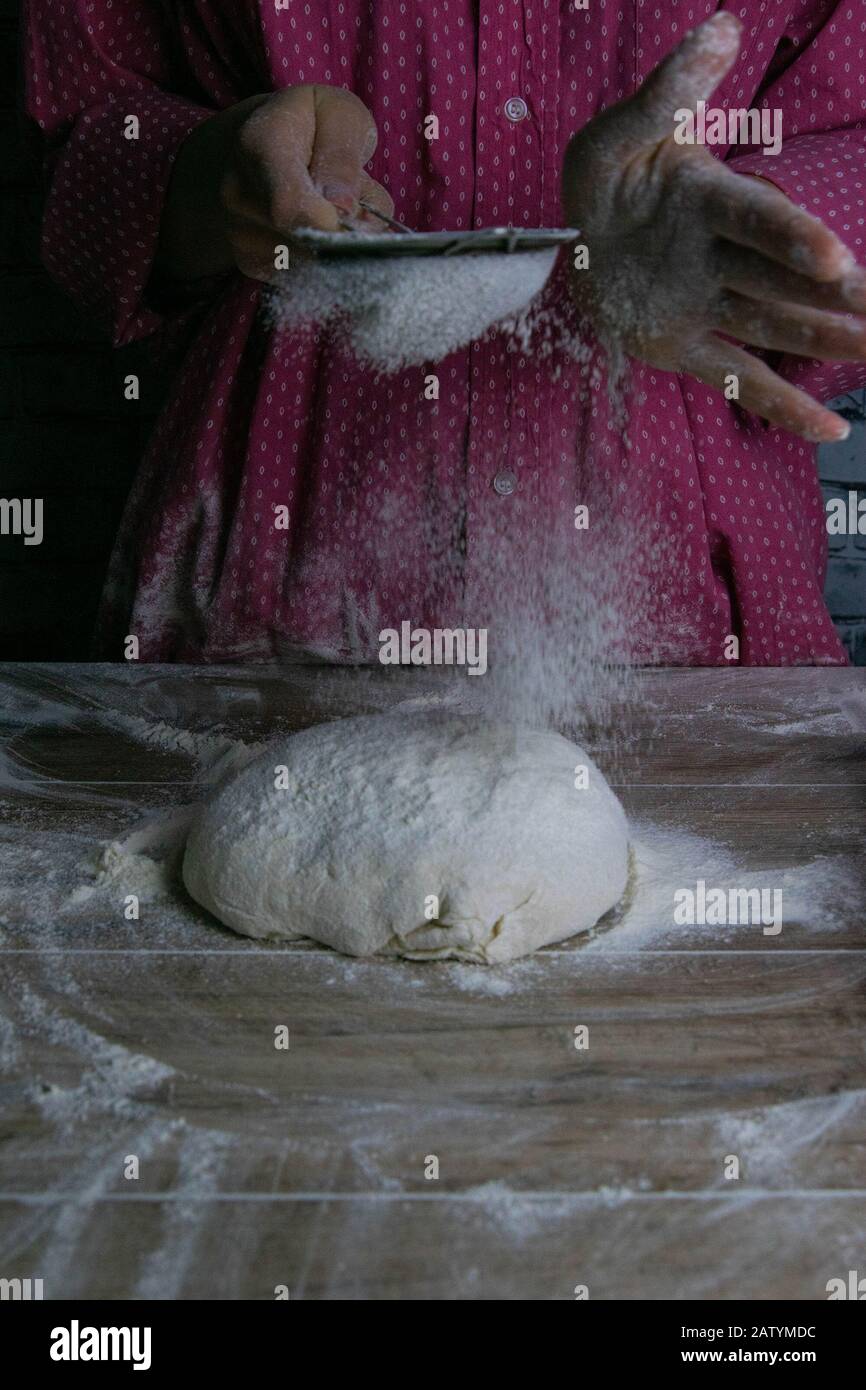 The woman sprinkles flour dough from the fullness for sifting flour ...