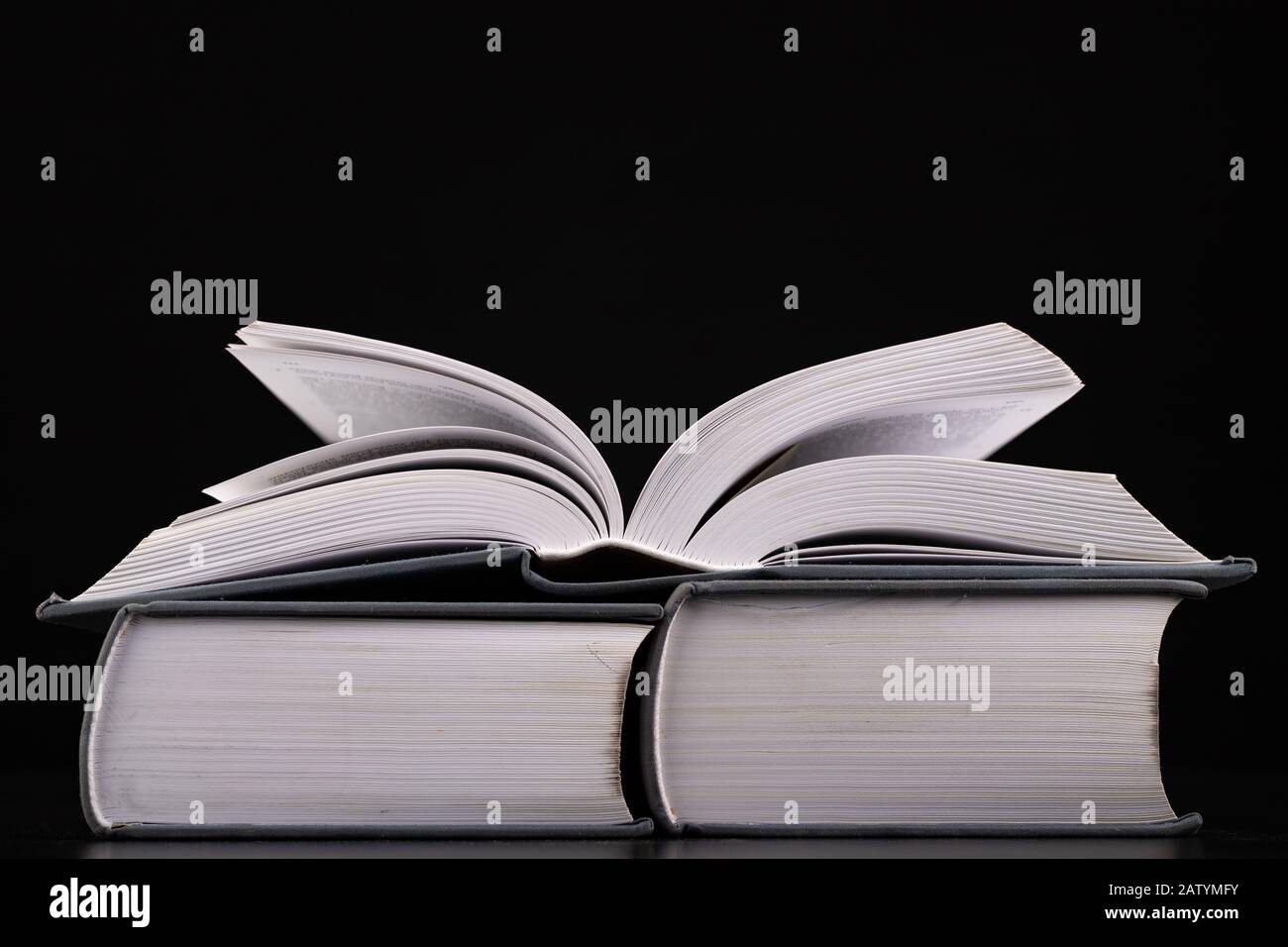 An open thick book on a stack of other books. Extensive books ...