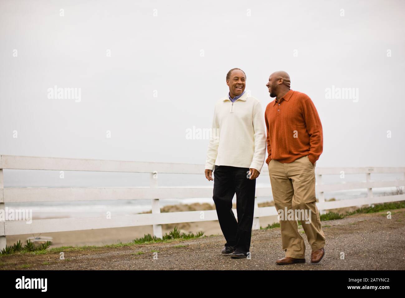 Men walking side by side along a beachside pavement Stock Photo - Alamy