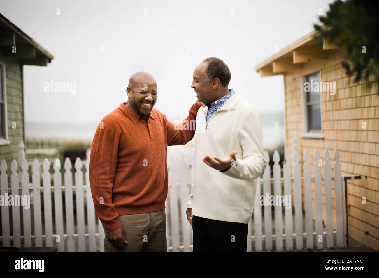 Two men sharing a laugh in between houses Stock Photo - Alamy