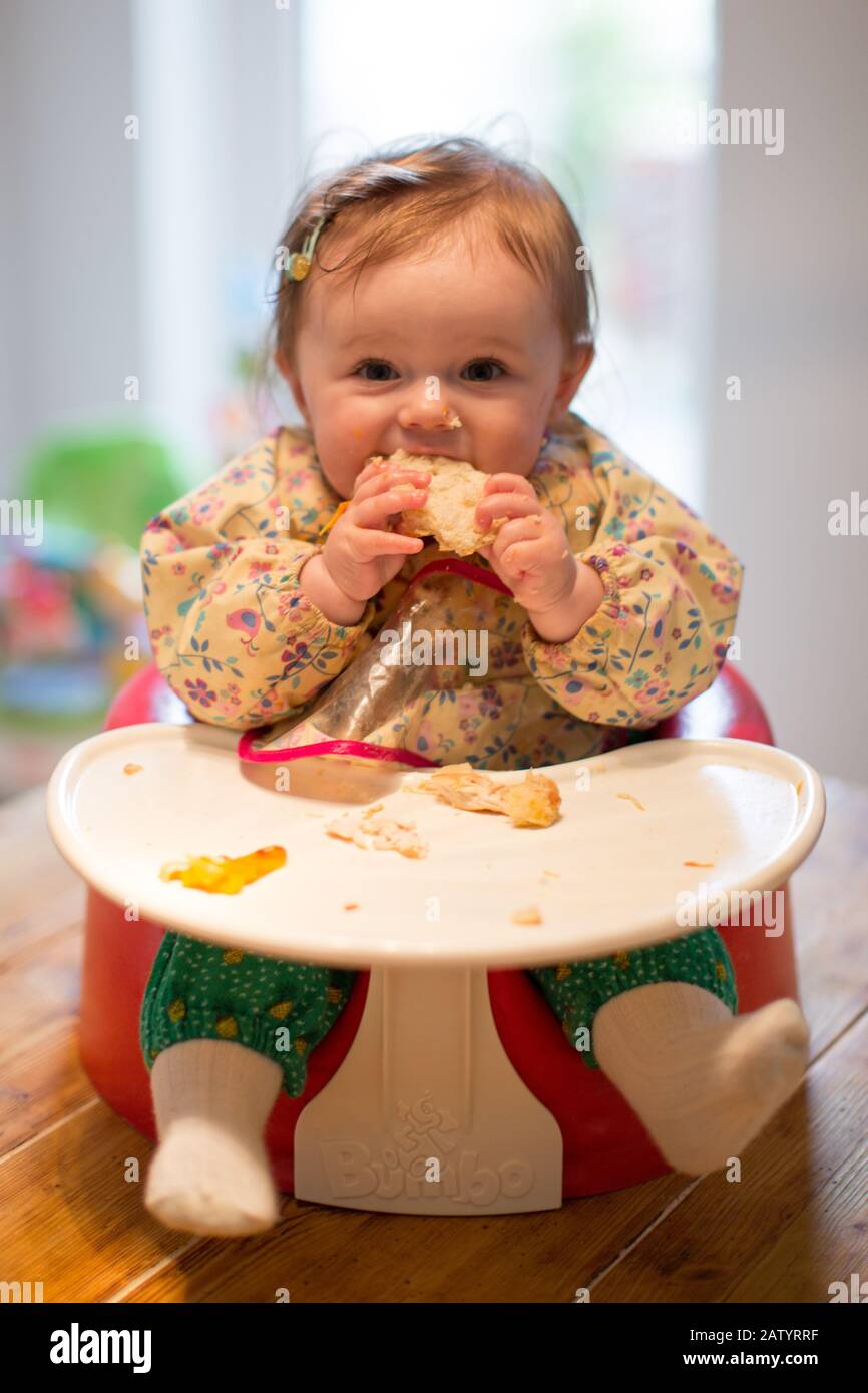8 month old baby girl in a bumbo eating food Stock Photo - Alamy