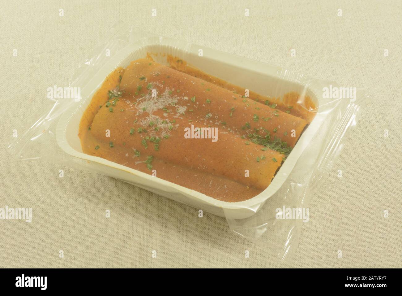 Two frozen enchiladas in paper microwave container with plastic ...