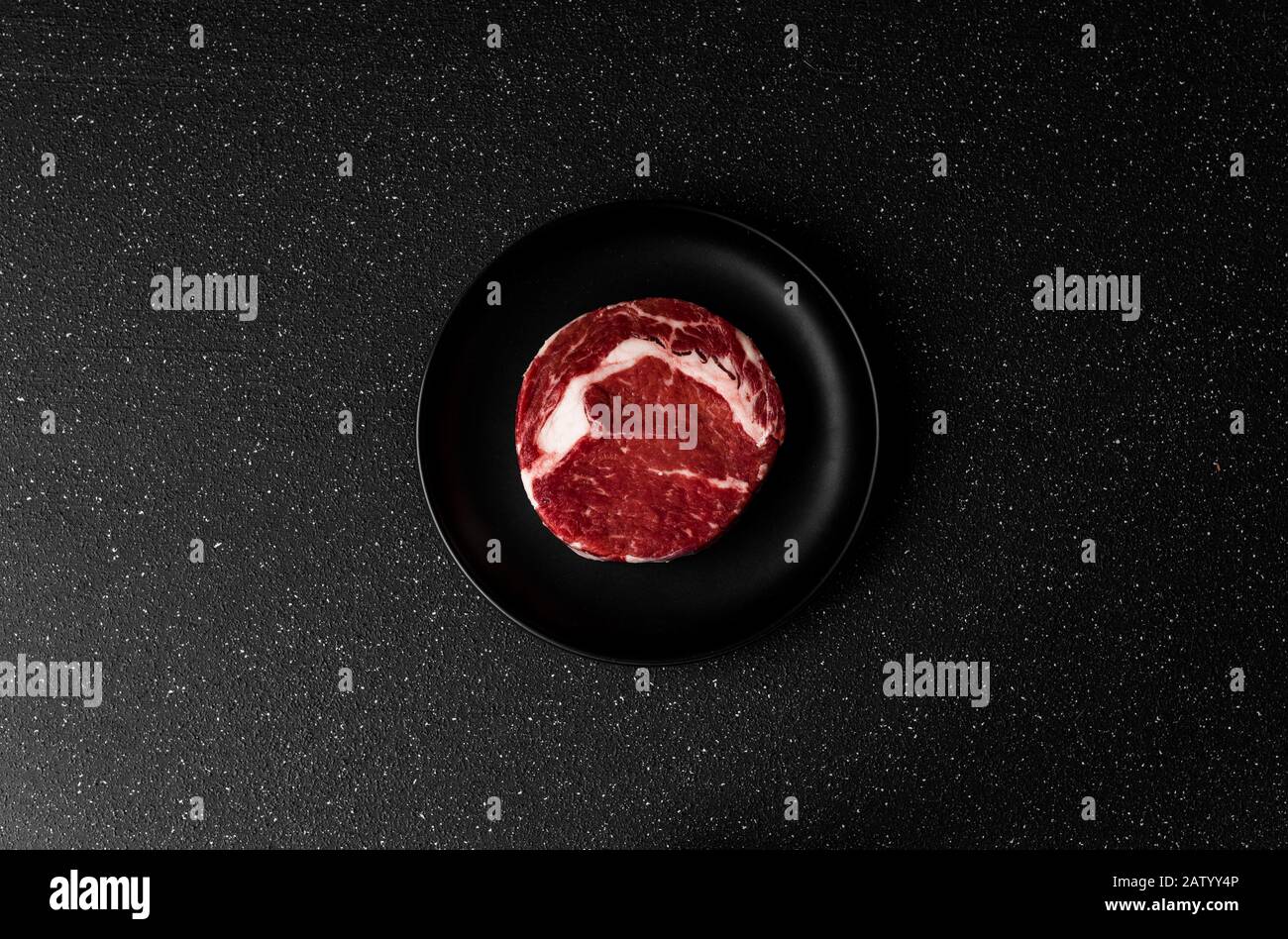 Raw prime beef rib eye meat food steak against black stone background ...